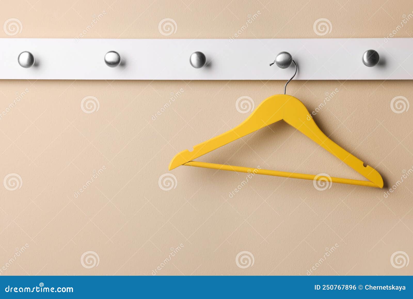Rack with Empty Yellow Clothes Hanger on Beige Wall Stock Photo - Image ...