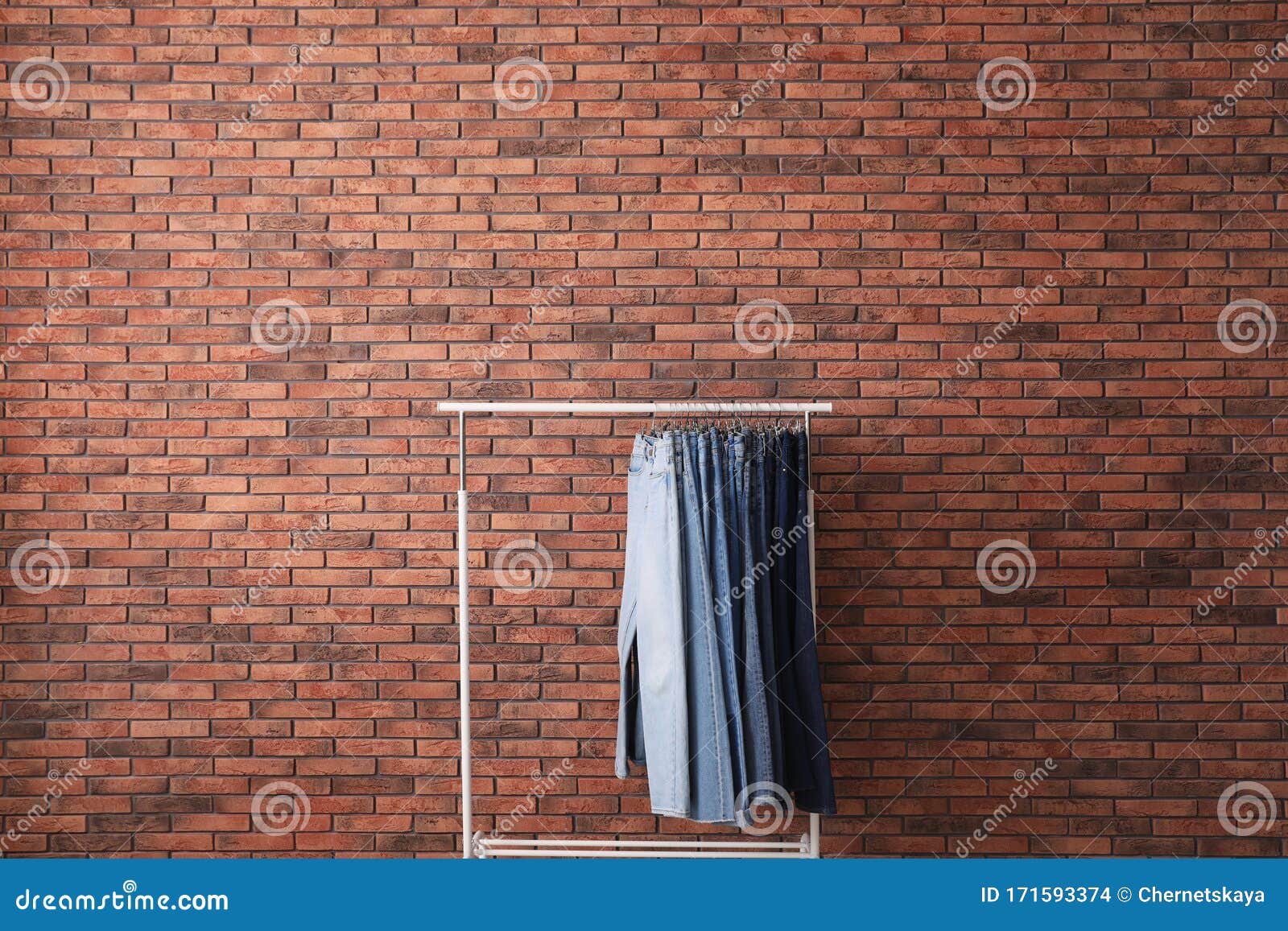 Rack with Stylish Jeans Near Wall Stock Photo - Image of blue, pants ...
