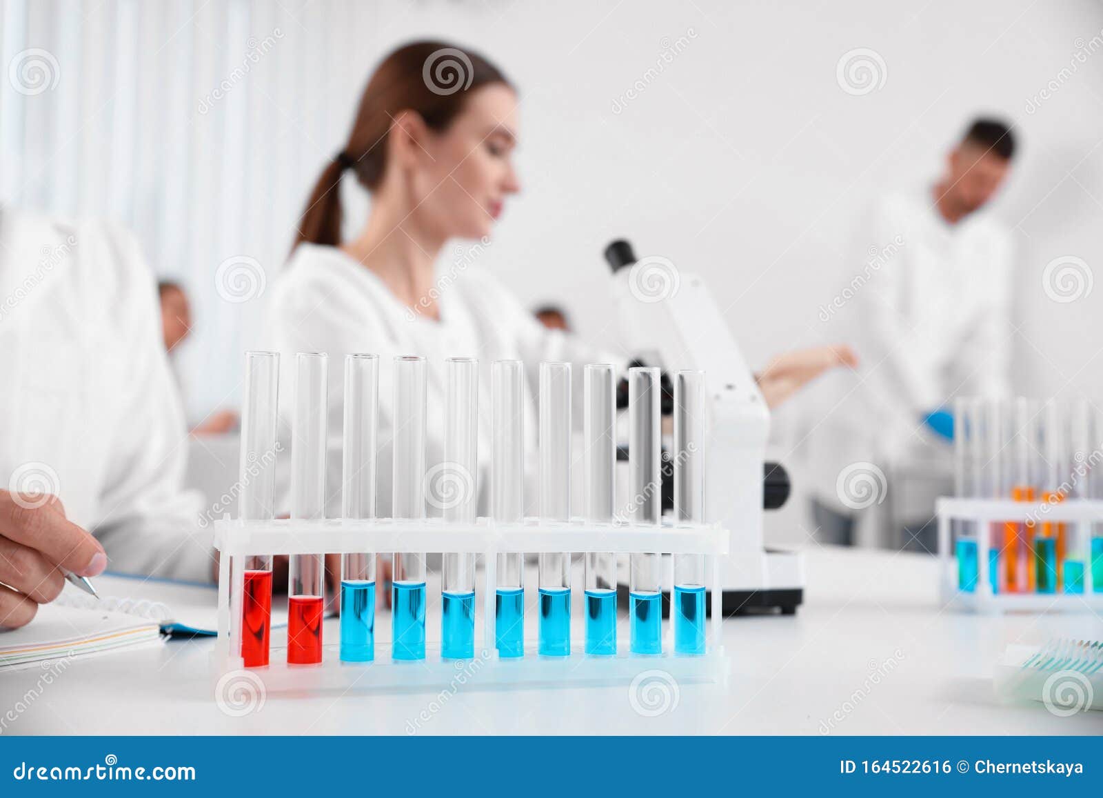 Rack with Test Tubes on White Table and Scientists. Medical Research ...
