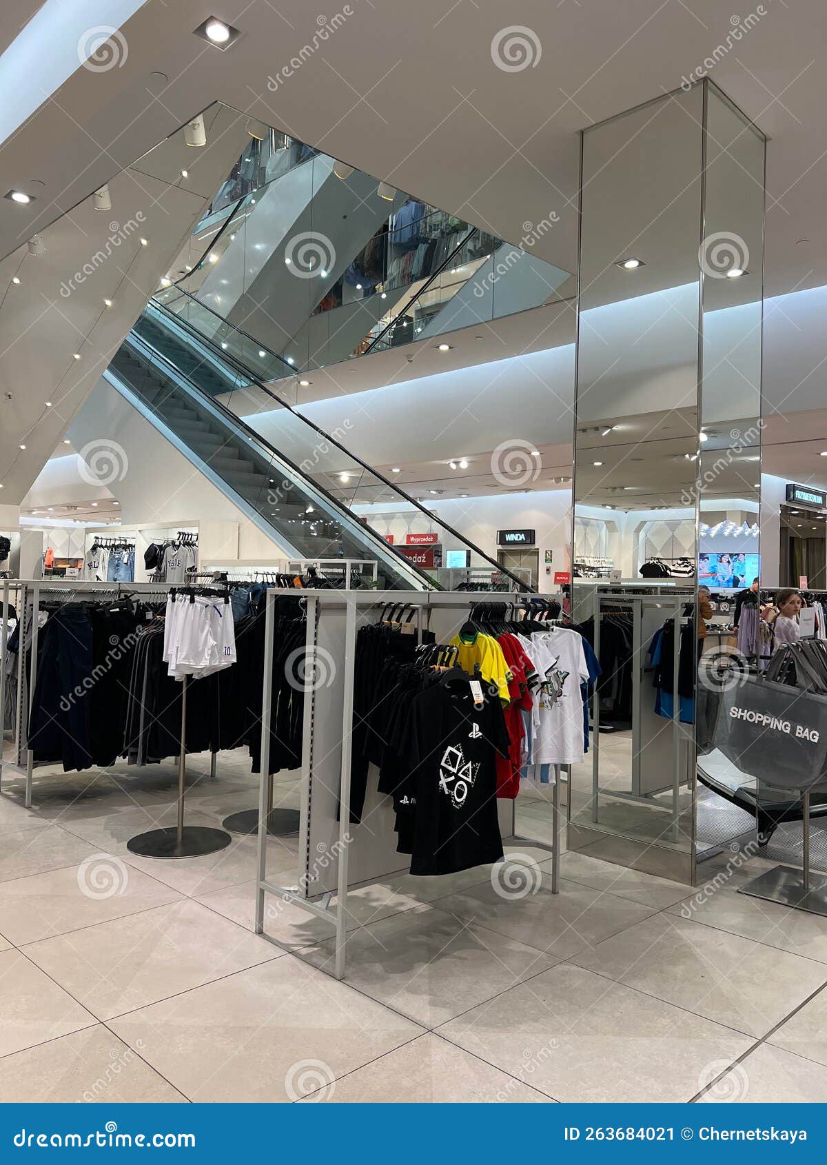 Racks with Stylish Clothes and Escalator in Shopping Mall Editorial ...