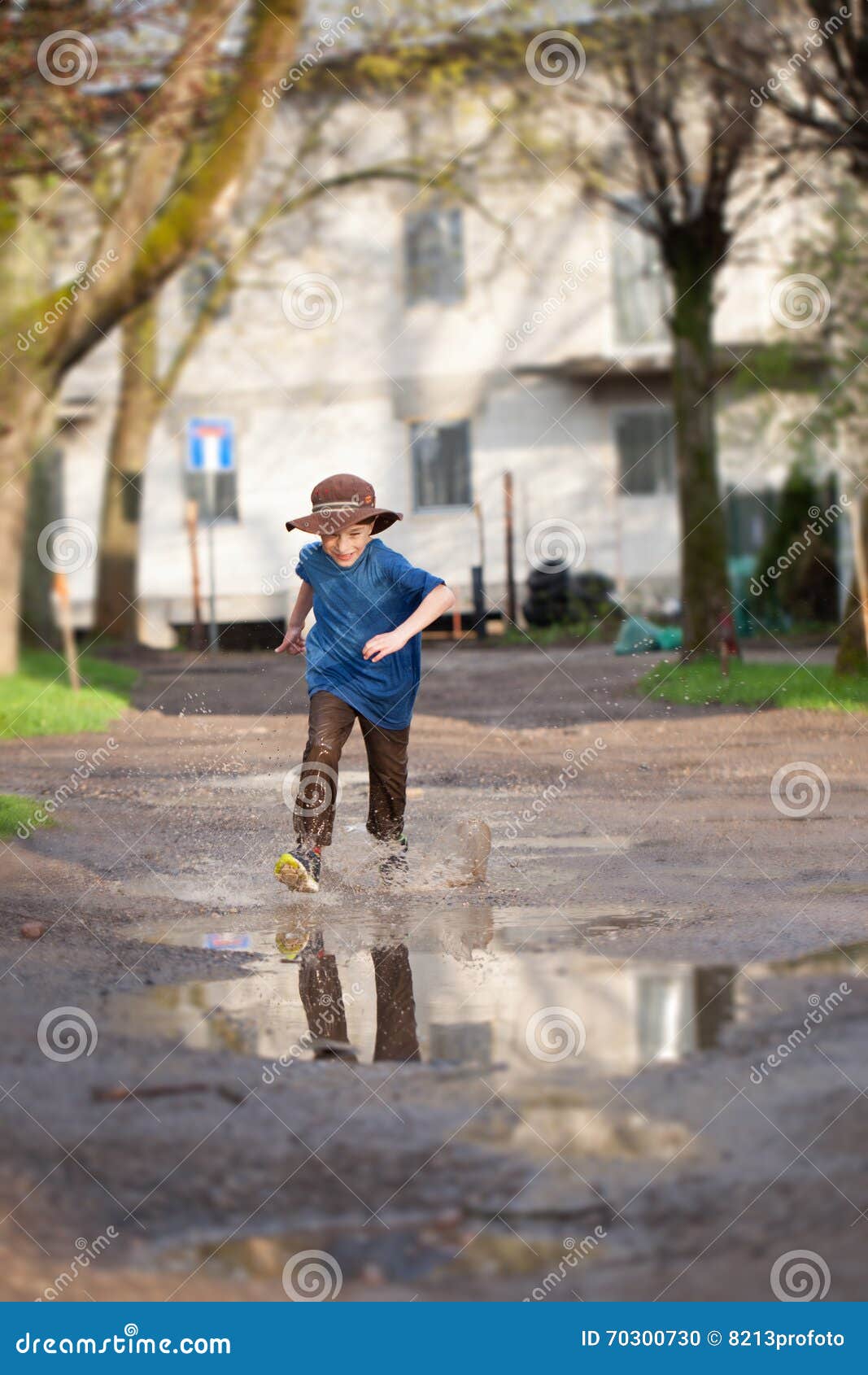 Ragazzino Che Spruzza in Una Pozza Di Fango, Fotografia Stock ...