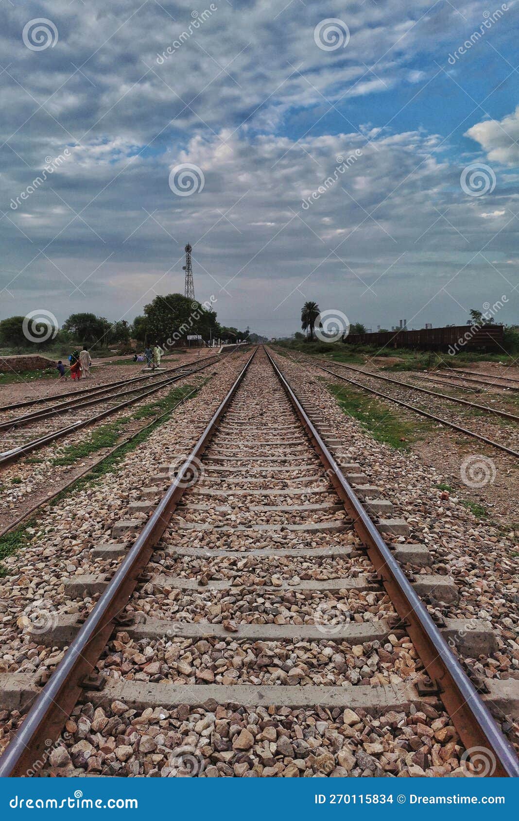 A Railway Track with Blue Sky Filled with Clouds and Trees on Horizon ...