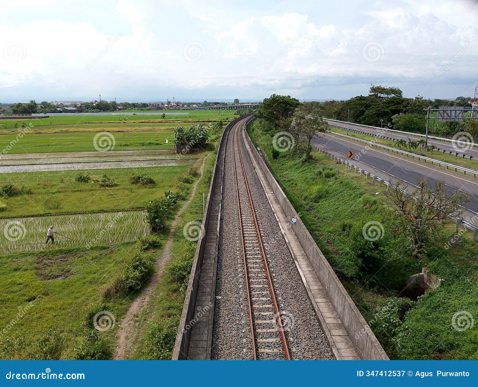 Railway Tracks Run between Vast Rice Fields and a Highway Under a ...