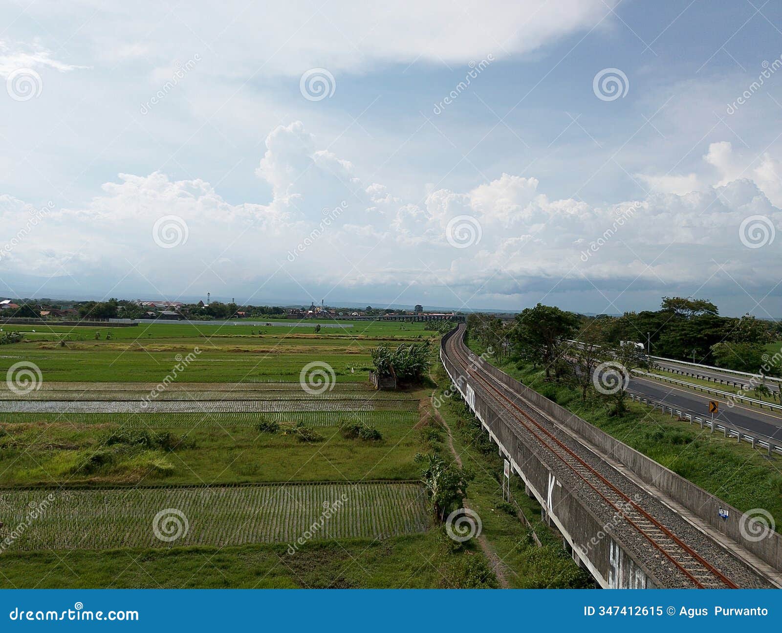 Railway Tracks Run between Vast Rice Fields and a Highway Under a ...
