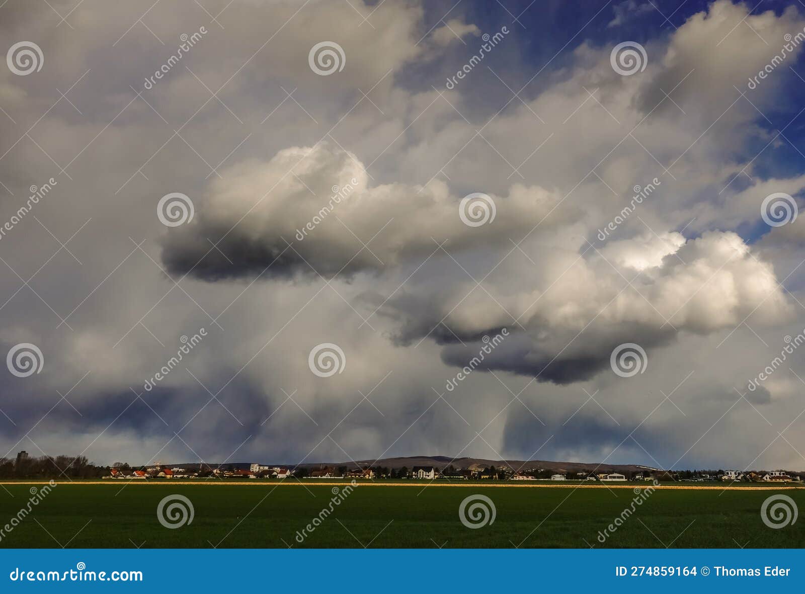 Rain Clouds Over a Village and Fresh Green Fields in the Foreground ...