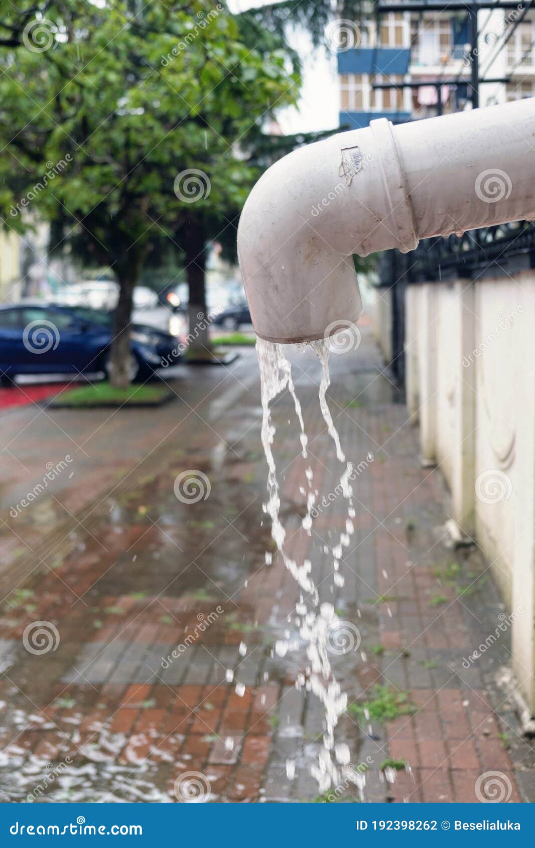 Rain Water is Pouring from the White Draining Gutter on the Pavement ...