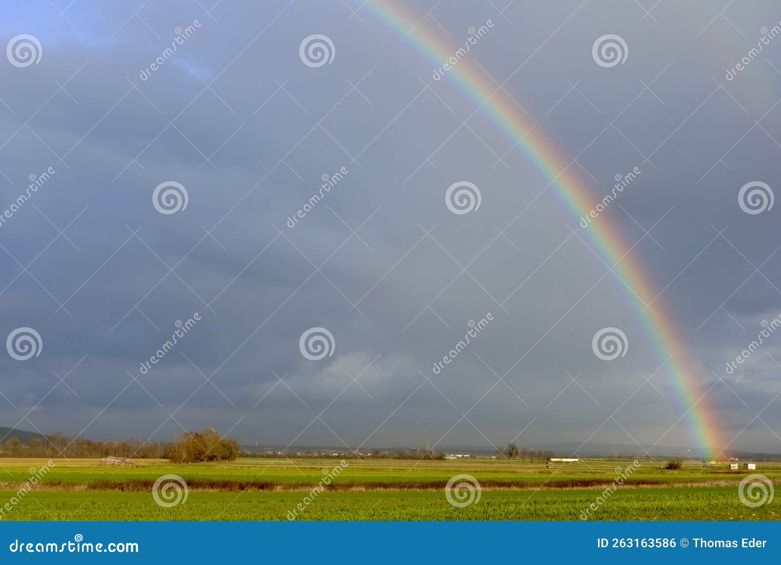 Rainbow on Dark Rain Clouds Over Green Fields in a Flat Landscape Stock ...