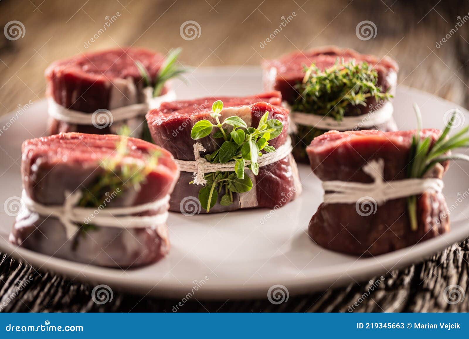 Raw Beef Steak Cuts on a Plate Wrapped with Strings and Fresh Herbs ...