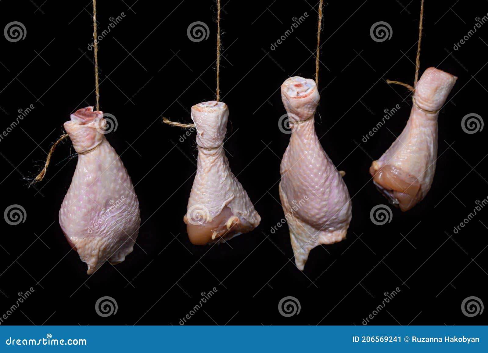 Raw Chicken Legs on a Black Background. Chicken Legs Hang Suspended by ...