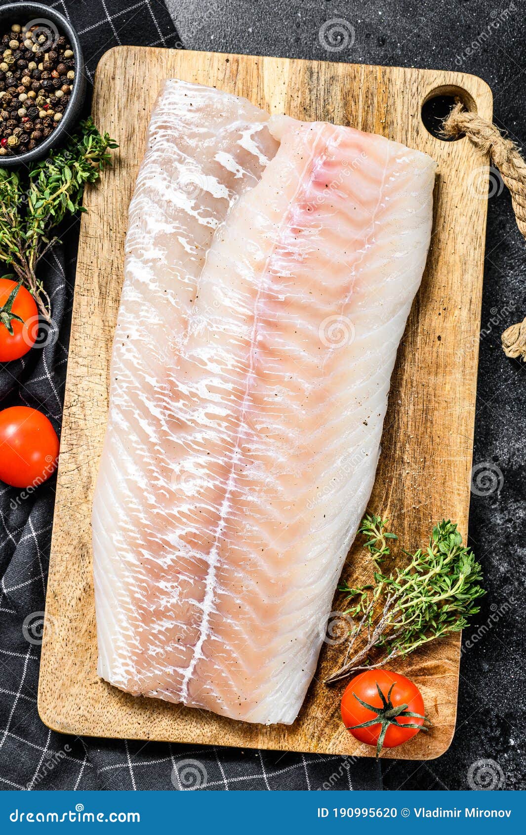 Raw Cod Fillet with and Herbs on Rustic Wooden Cutting Board. Black ...