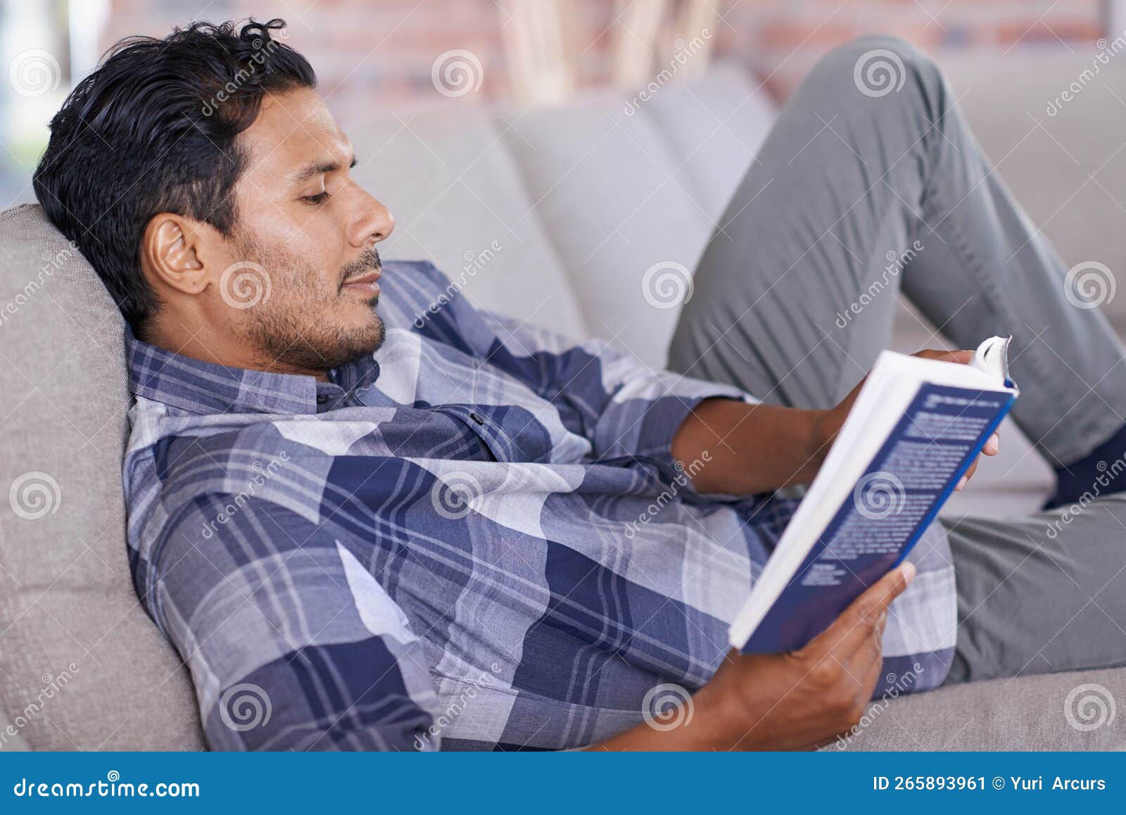 Reading and Relaxing. a Young Man Reading a Novel while Relaxing on the ...