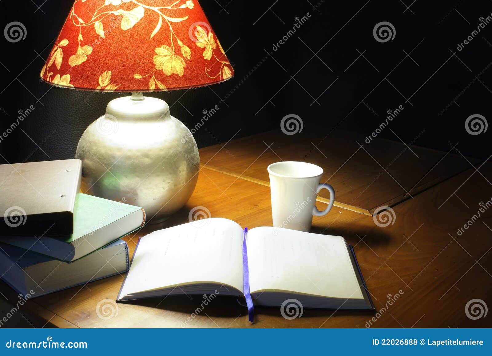 A Table Lamp, a White Cup, an Open Book, Some Books, on a Brown Table ...