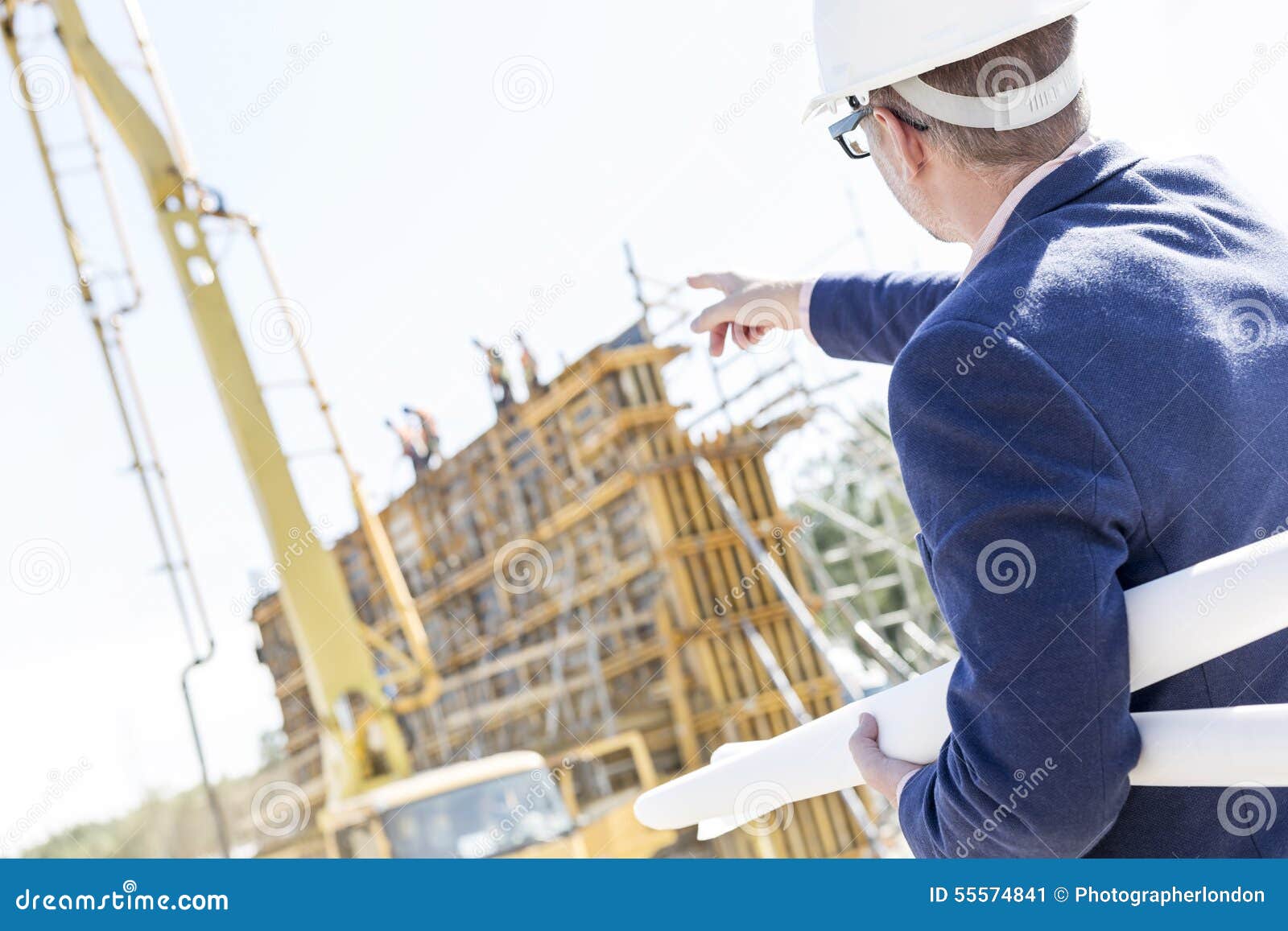 Rear View of Architect Holding Blueprints while Pointing at ...