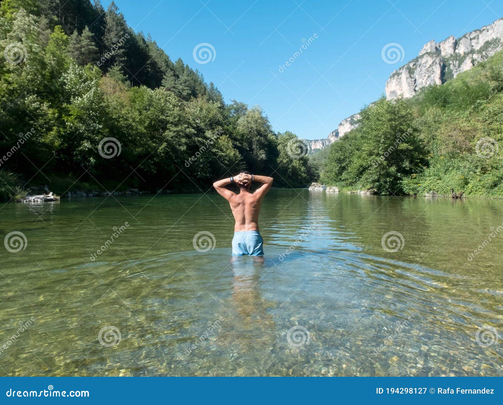 Rear View of a Arms Raised Male Standing into the River while Ba Stock ...