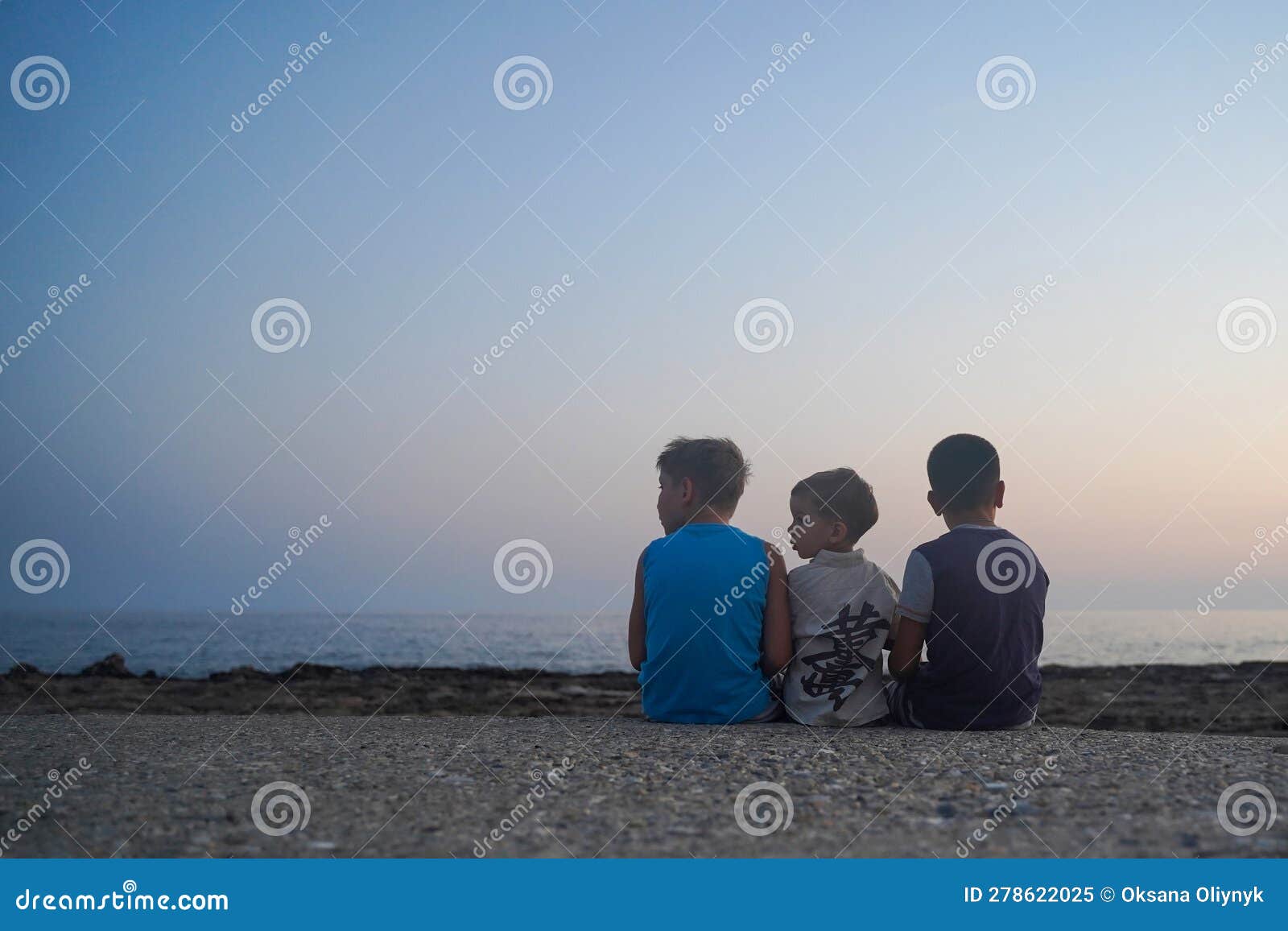 Rear View of Children Sitting in Front of the Sea and Looking Sideways ...