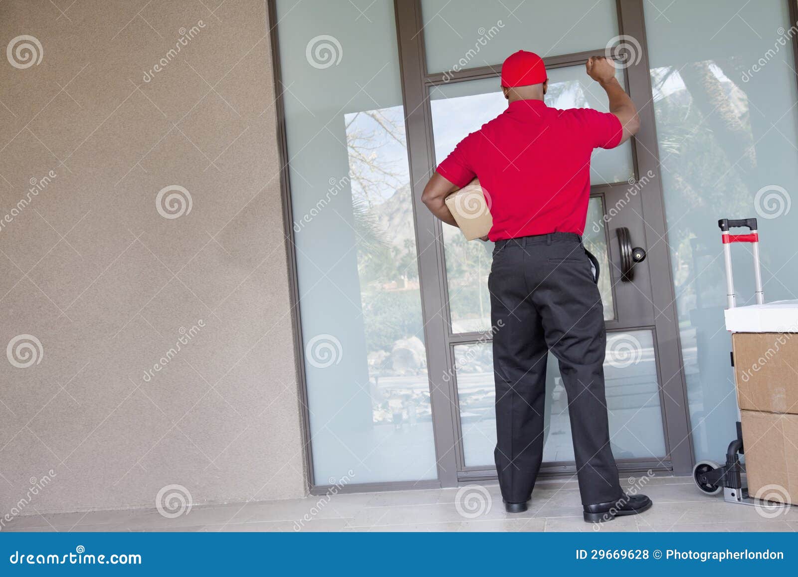 Rear View of a Delivery Man with Packages Knocking at Door Stock Photo ...