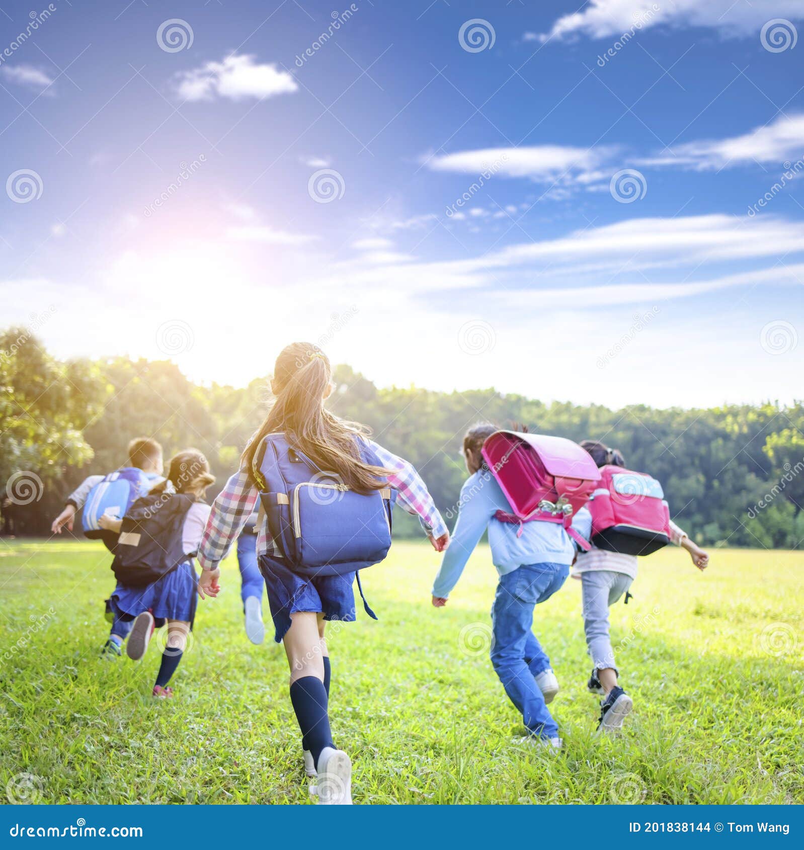 Rear View of Elementary School Kids Running on the Grass Stock Photo ...