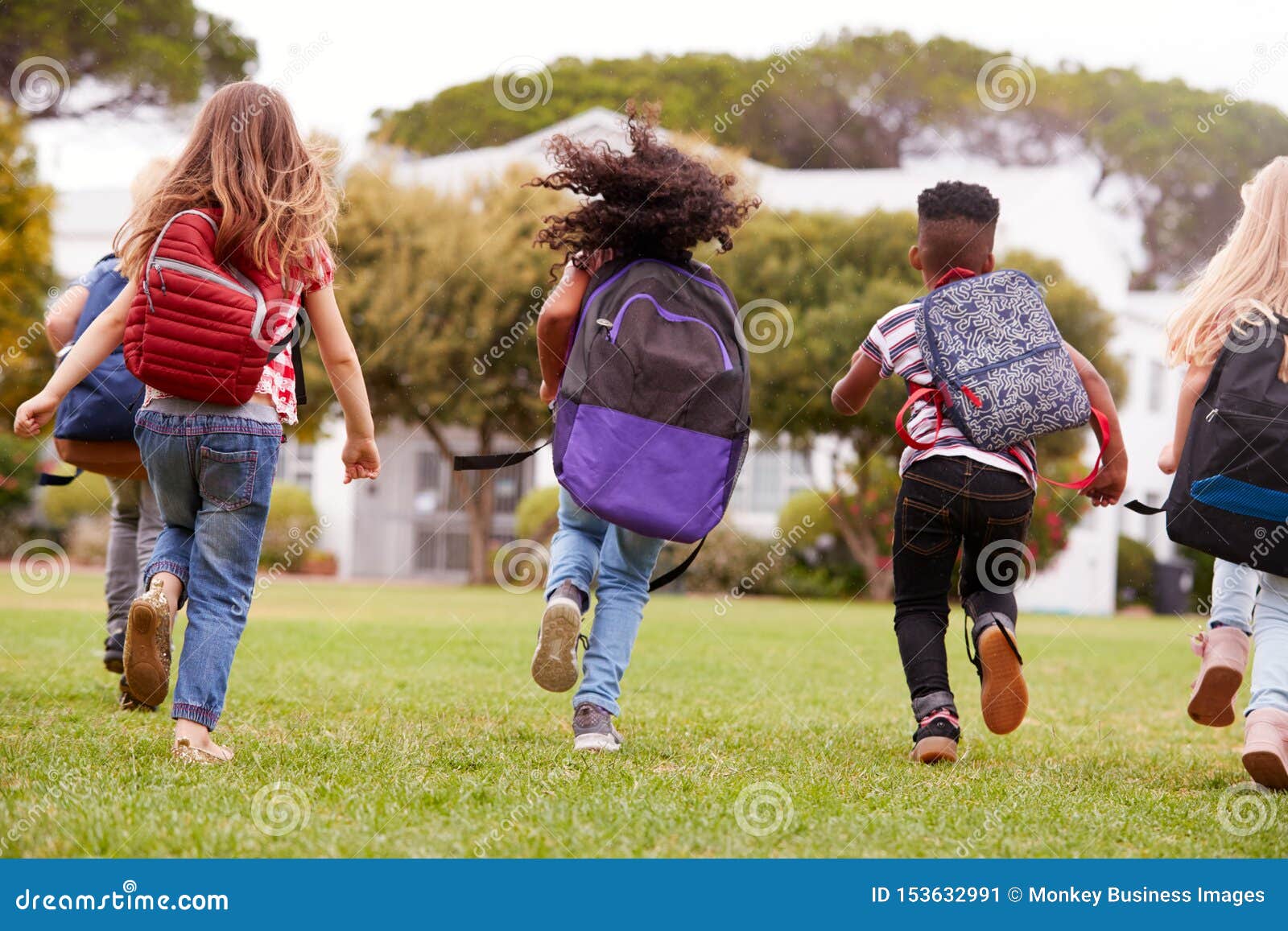 Rear View of Elementary School Pupils Running Across Field at Break ...