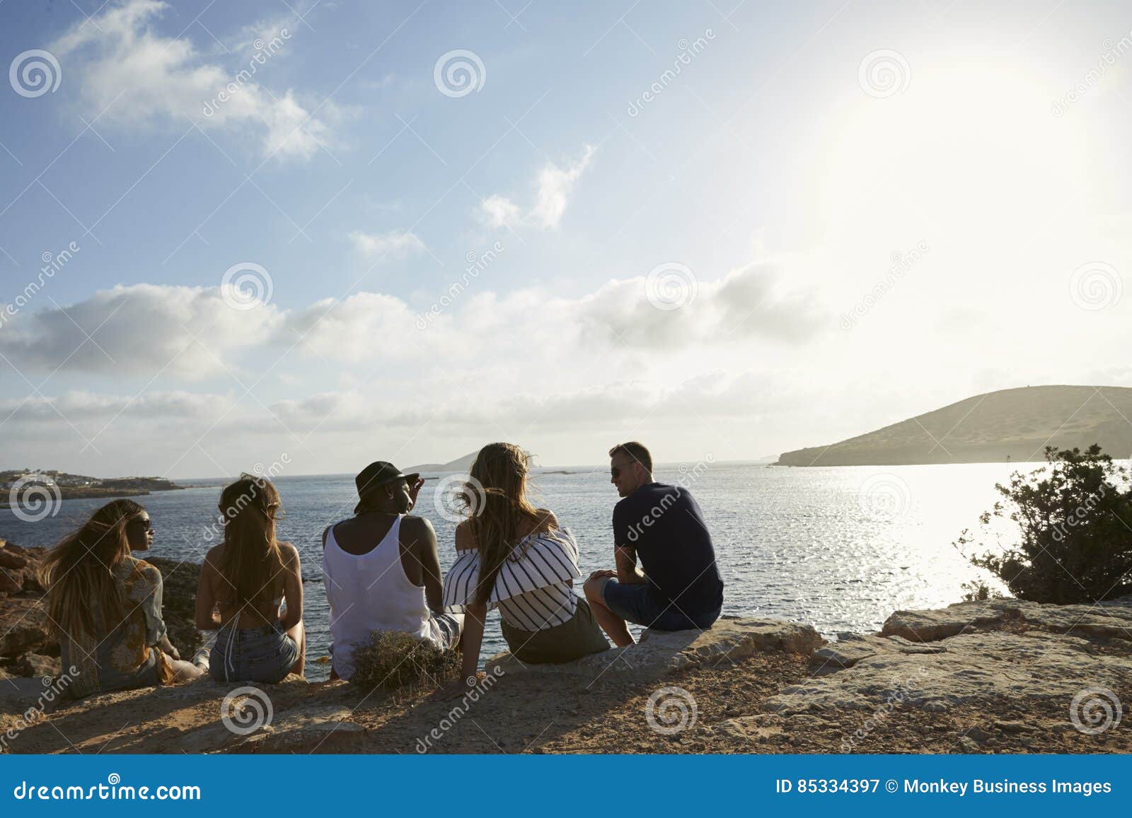 Rear View of Friends Sitting on Cliff Watching Sunset Stock Image ...