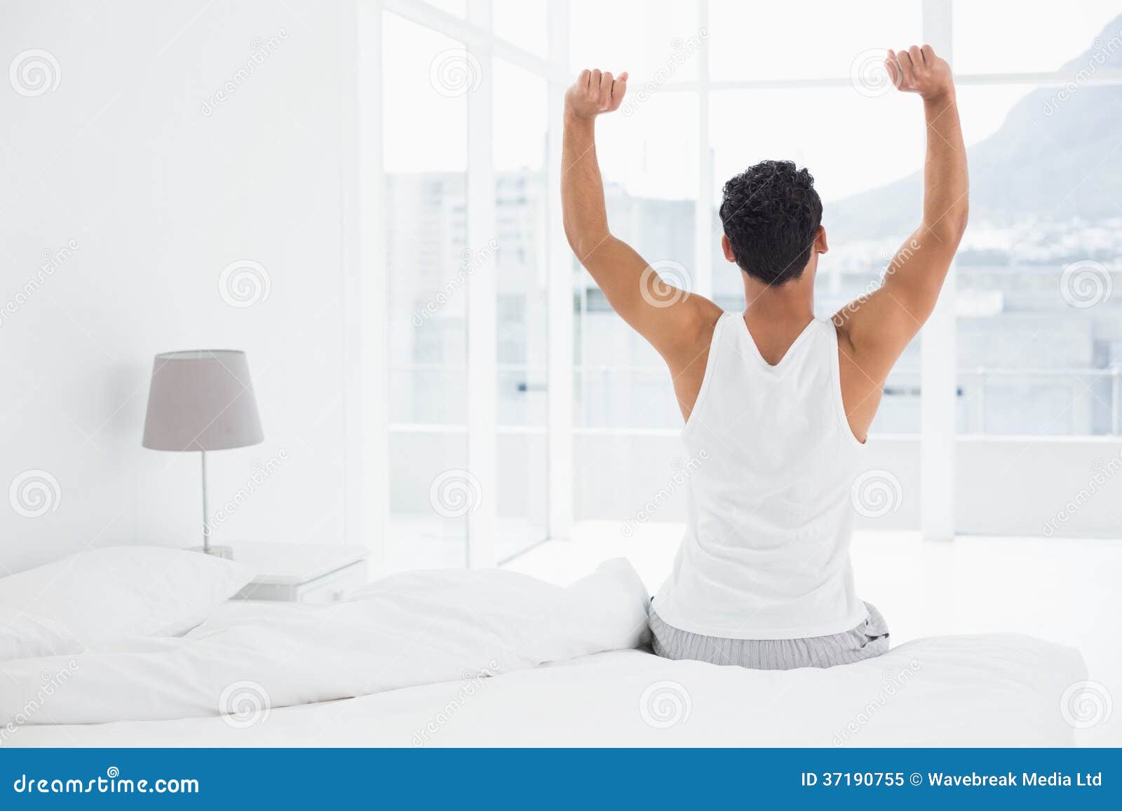 Rear View of a Man Stretching Arms in Bed Stock Image - Image of ...