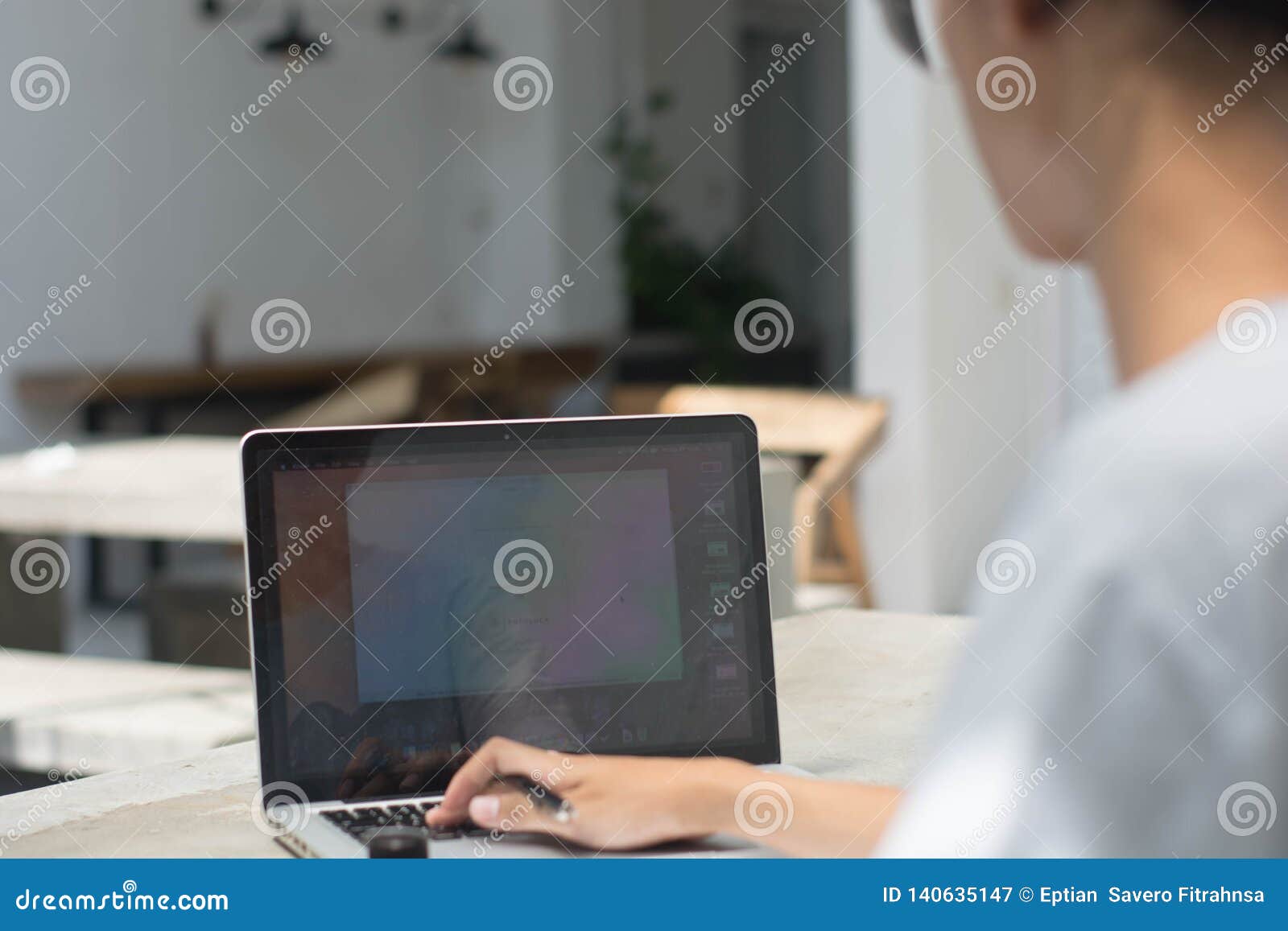 A Rear View Student Doing Homework with Laptop and Writing in Notebook ...