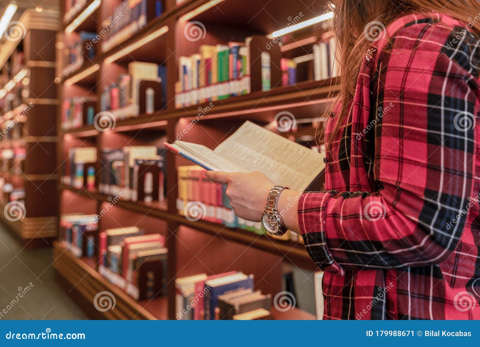 Rear View of Student Girl Standing in Library in Front of the Bookshelf ...