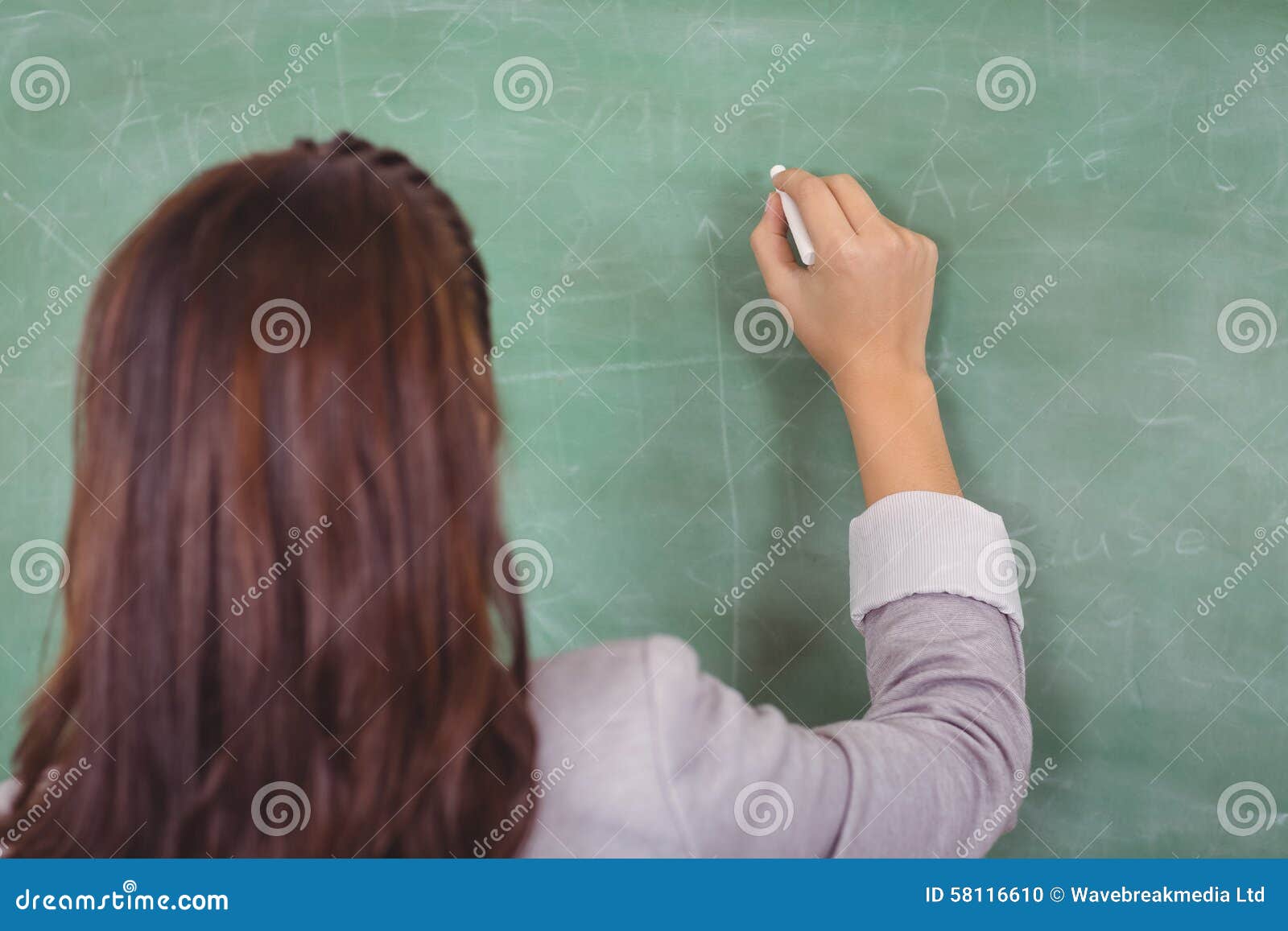 Rear View of Teacher Writing on Chalkboard in a Classroom Stock Photo ...