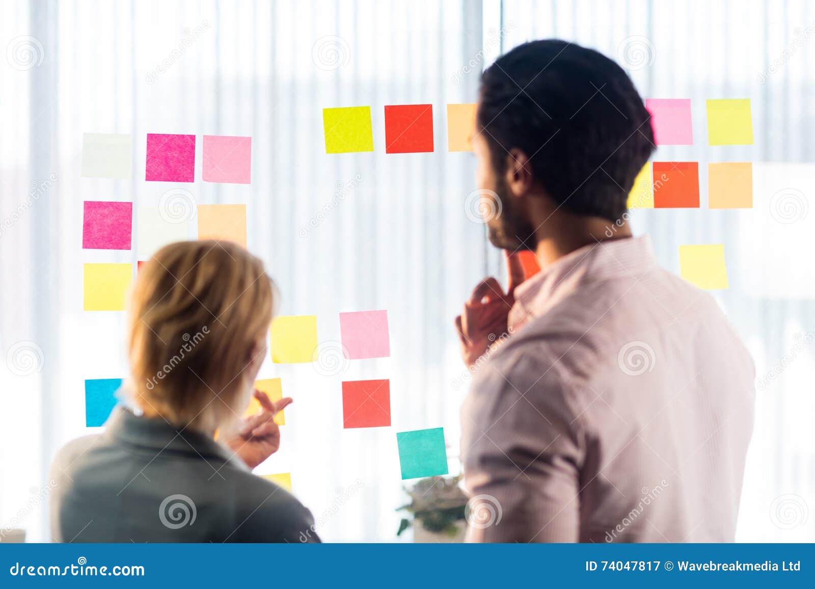 Rear View of Two Business People Looking at Post it Wall Stock Image ...