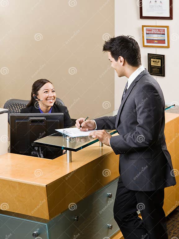 Receptionist Greeting Man at Front Desk Stock Image - Image of woman ...