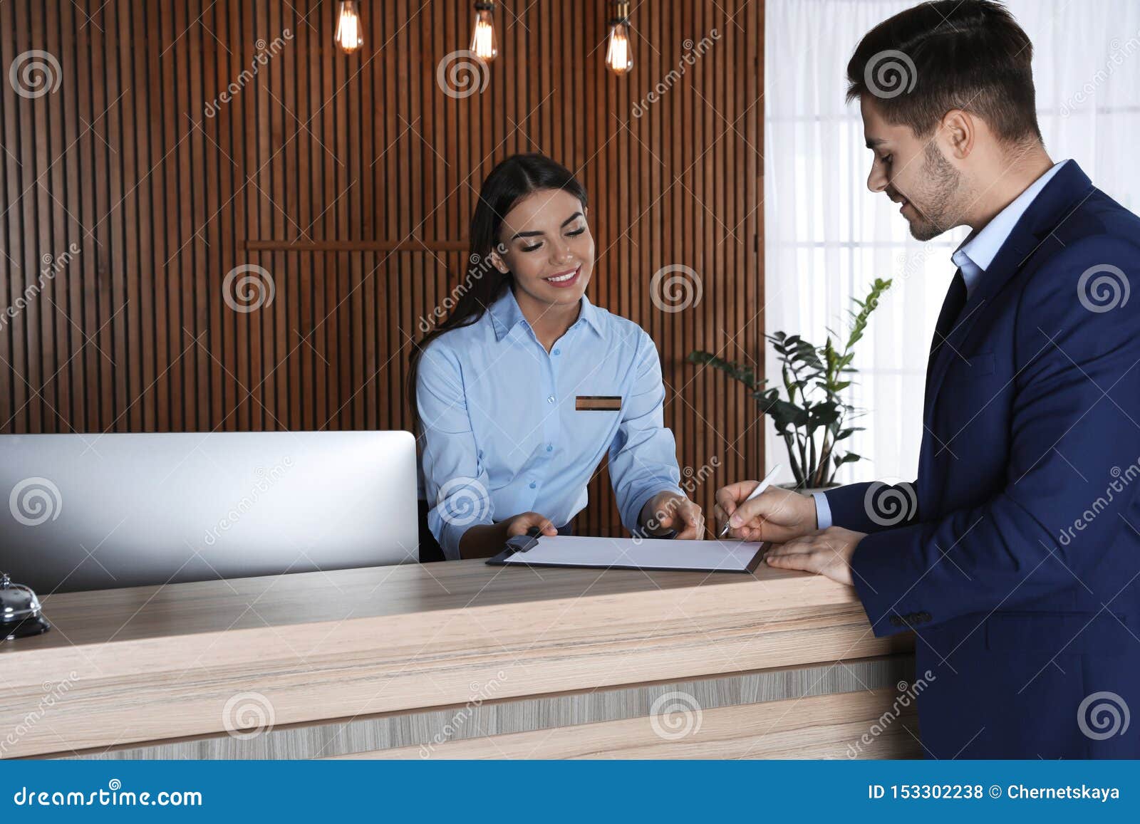 Receptionist Registering Client at Desk Stock Photo - Image of adult ...