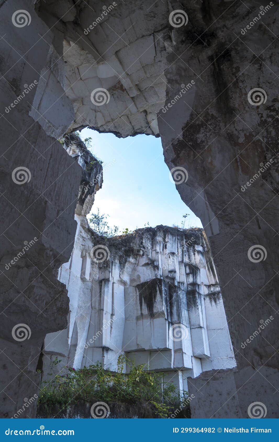 A Rectangular Opening in a Dark, Mossy Limestone Cave Frames a Bright ...