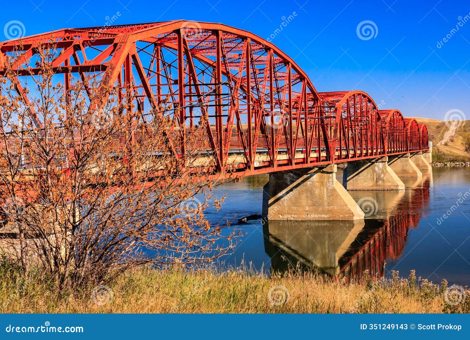 A Red Bridge Spans a River, with a Reflection of the Bridge in the ...
