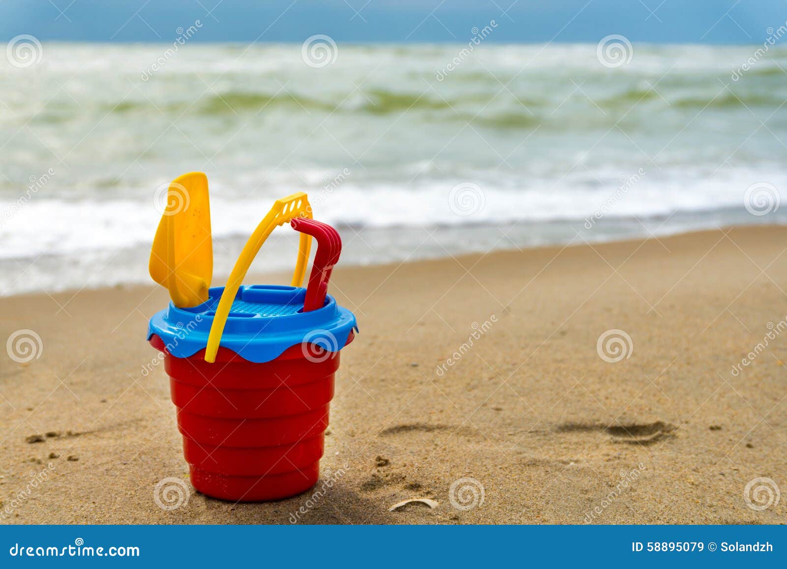 Red Bucket with a Shovel, a Rake and a Net on the Beach Stock Image ...