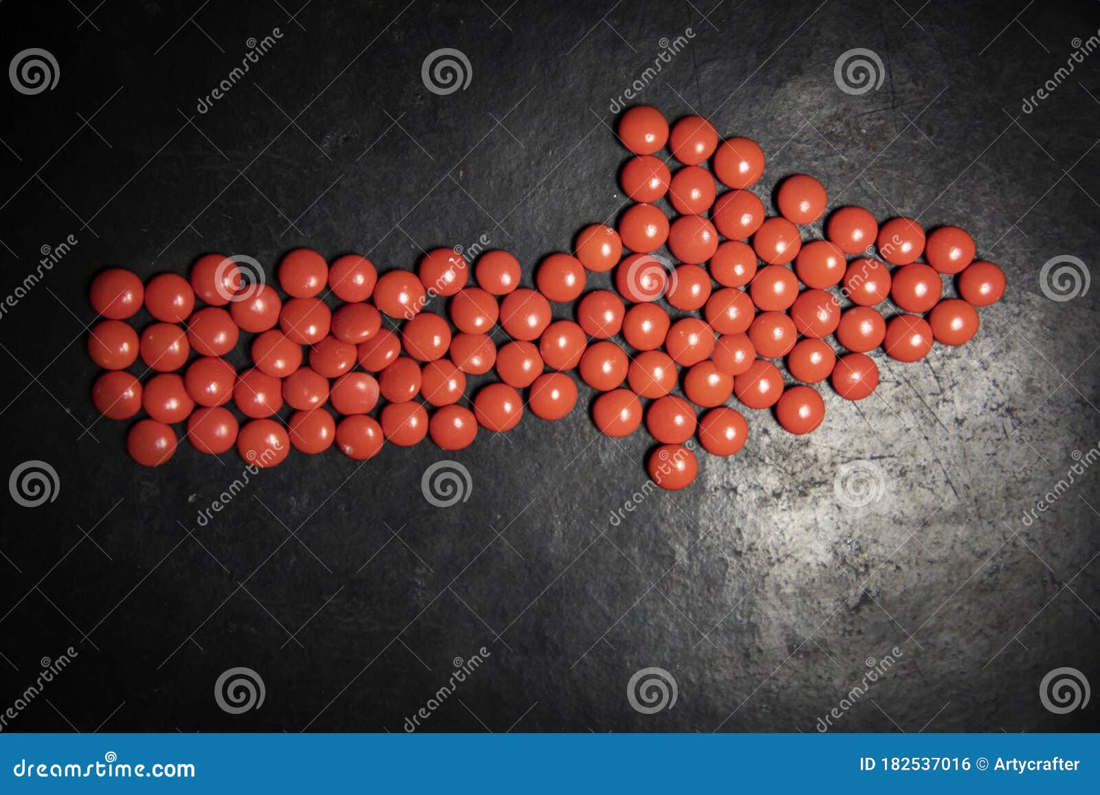 Red Candy Arranged in an Arrow on a Distressed Black Surface Stock ...