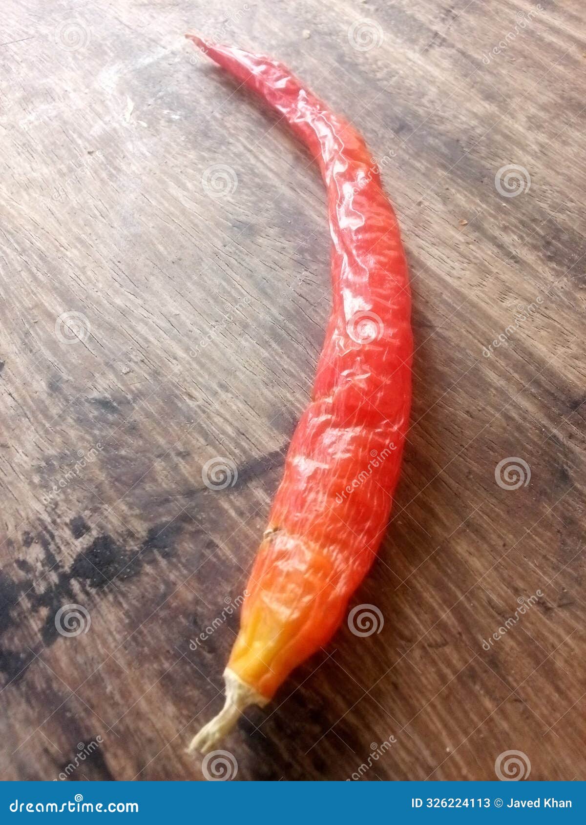 A Red Chilli is Shown in this Picture Which is on the Wooden Table ...