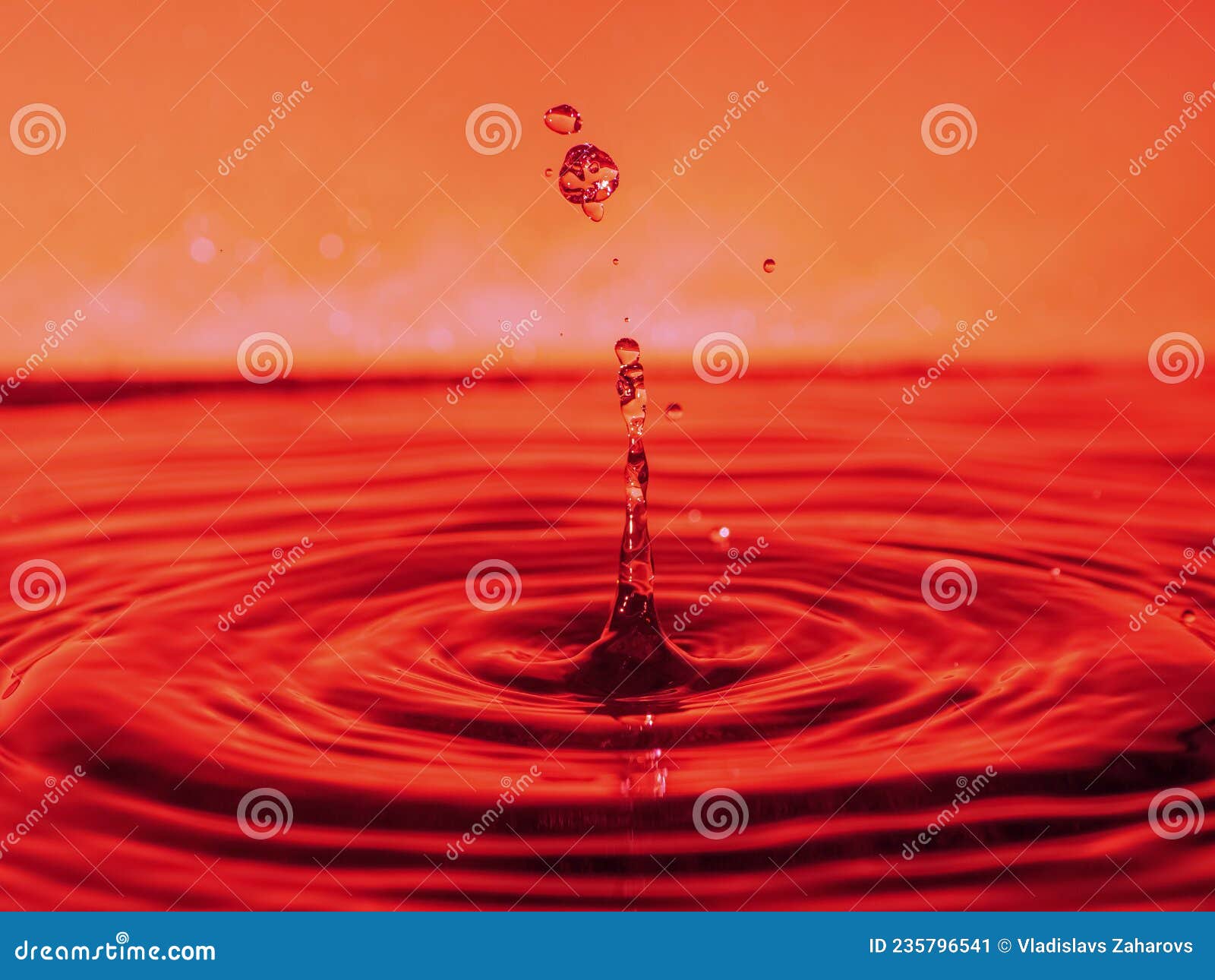 A Red Drop Drips into the Water and Creates Splashes of Different ...