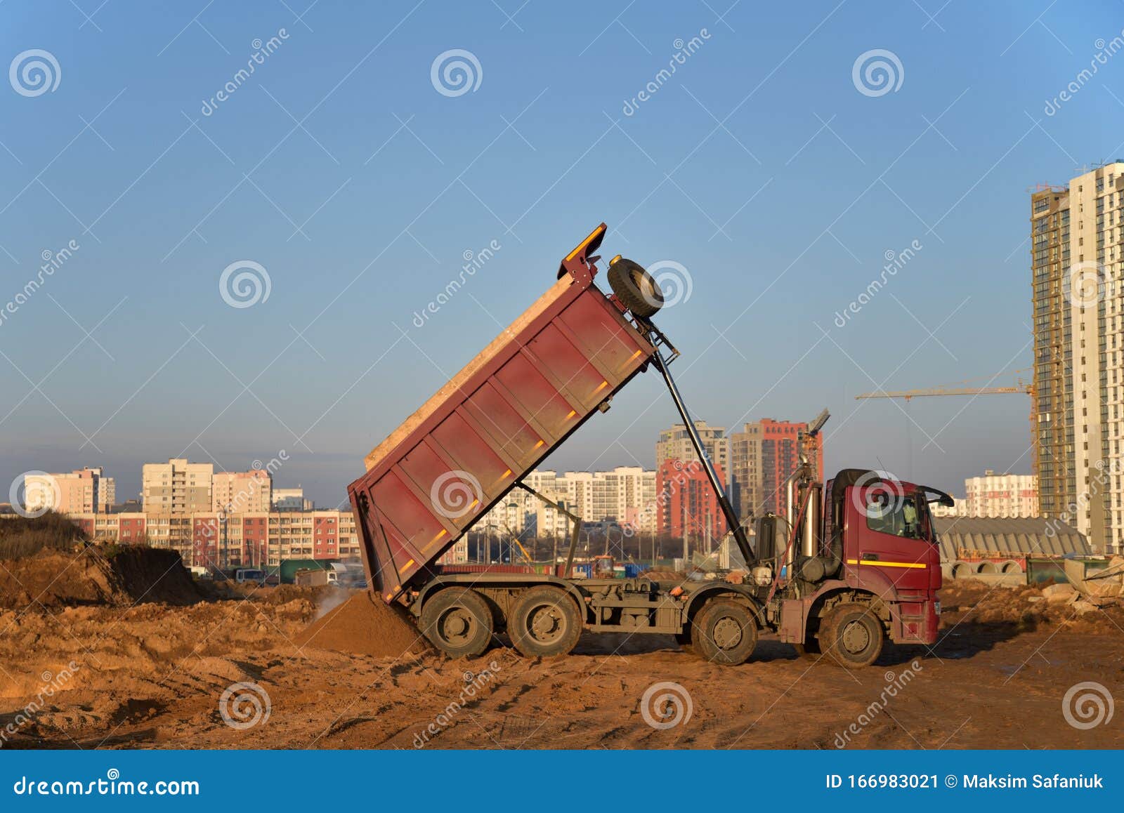 Red Dump Truck Dumps Its Load of Sand and Soil on Construction Site for ...