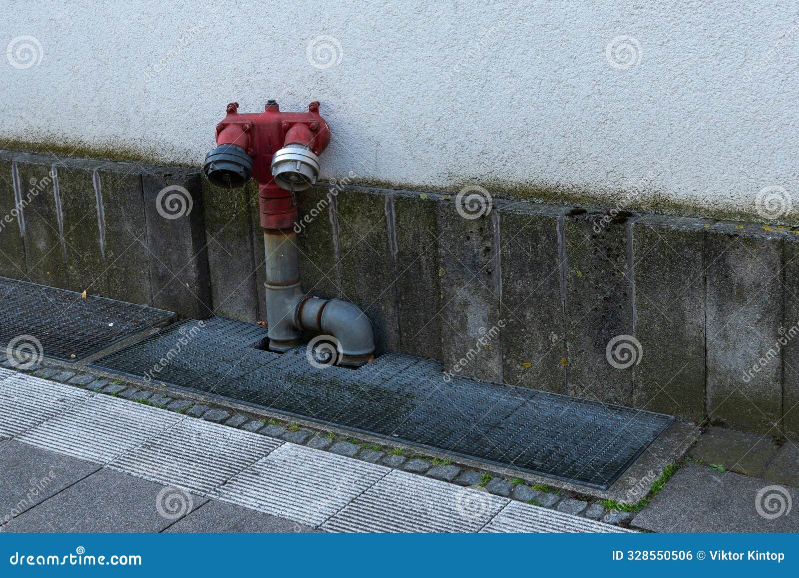 Red Fire Hydrant Positioned Alongside Concrete Wall with Attached Pipe ...