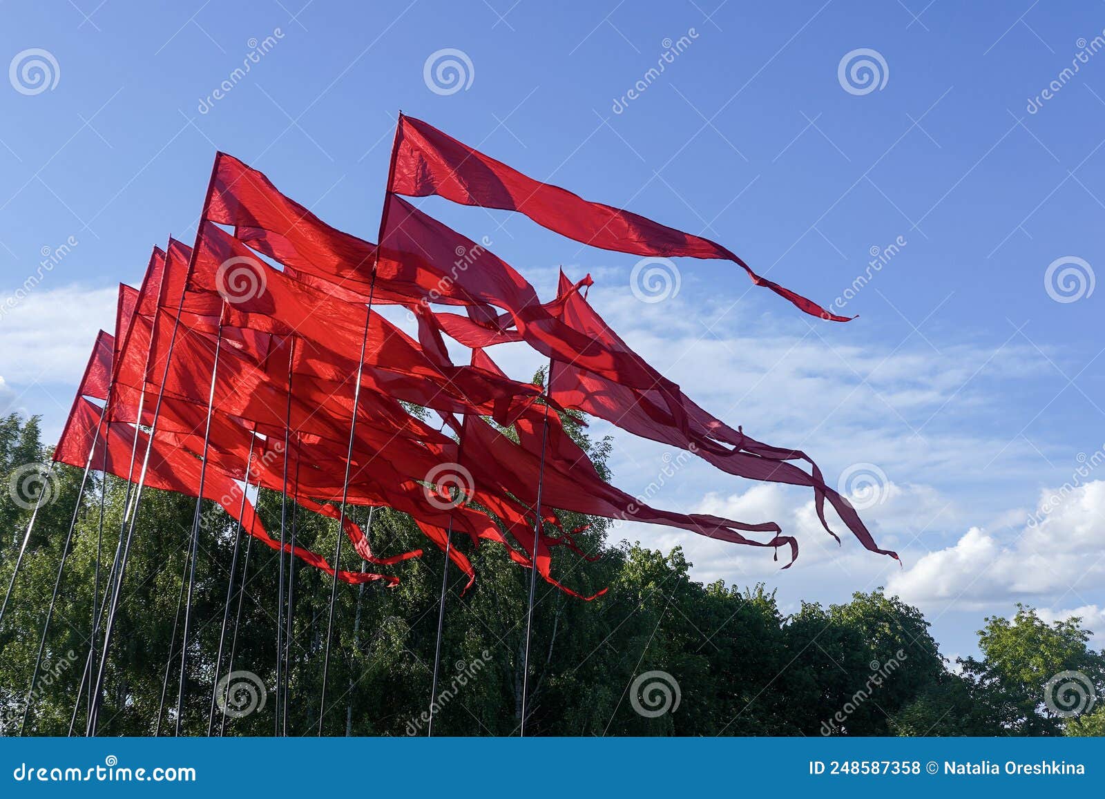 Red Flags Fluttering in the Wind with Blue Sky and Trees in the ...