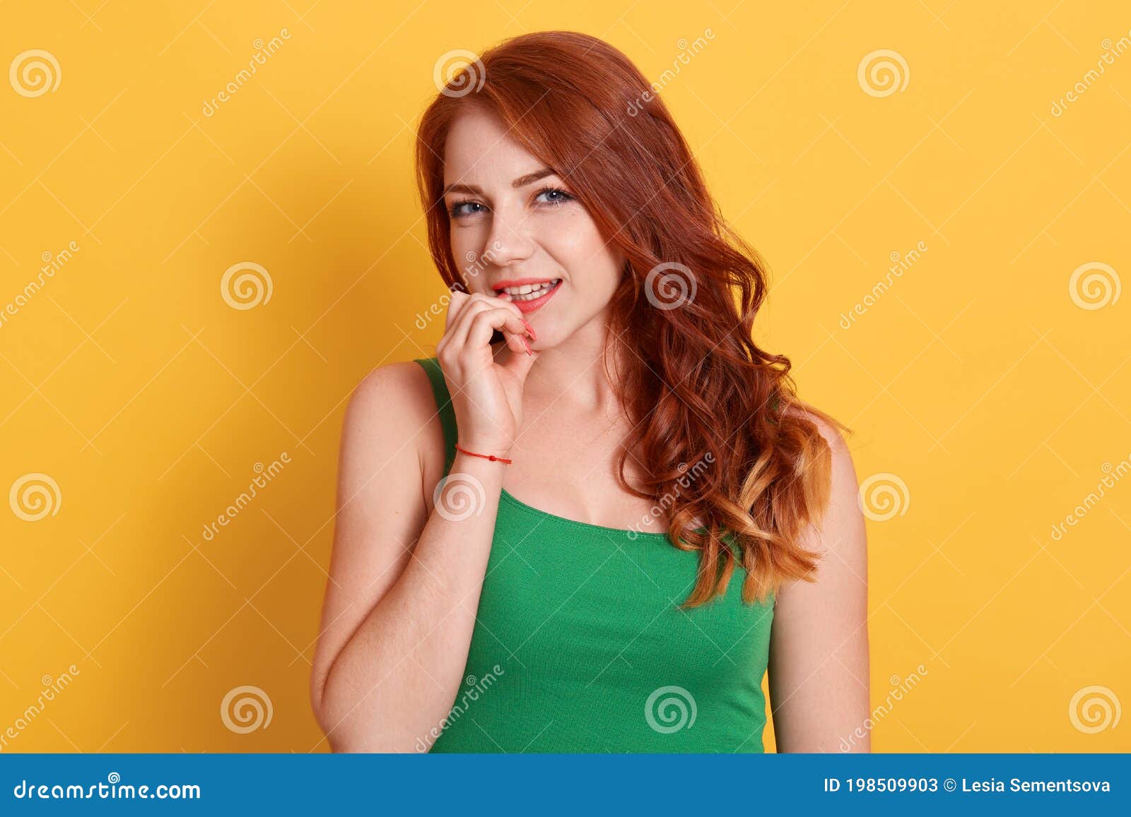 Red Haired Beautiful Smiling Girl Bites Her Finger And Looking Directly