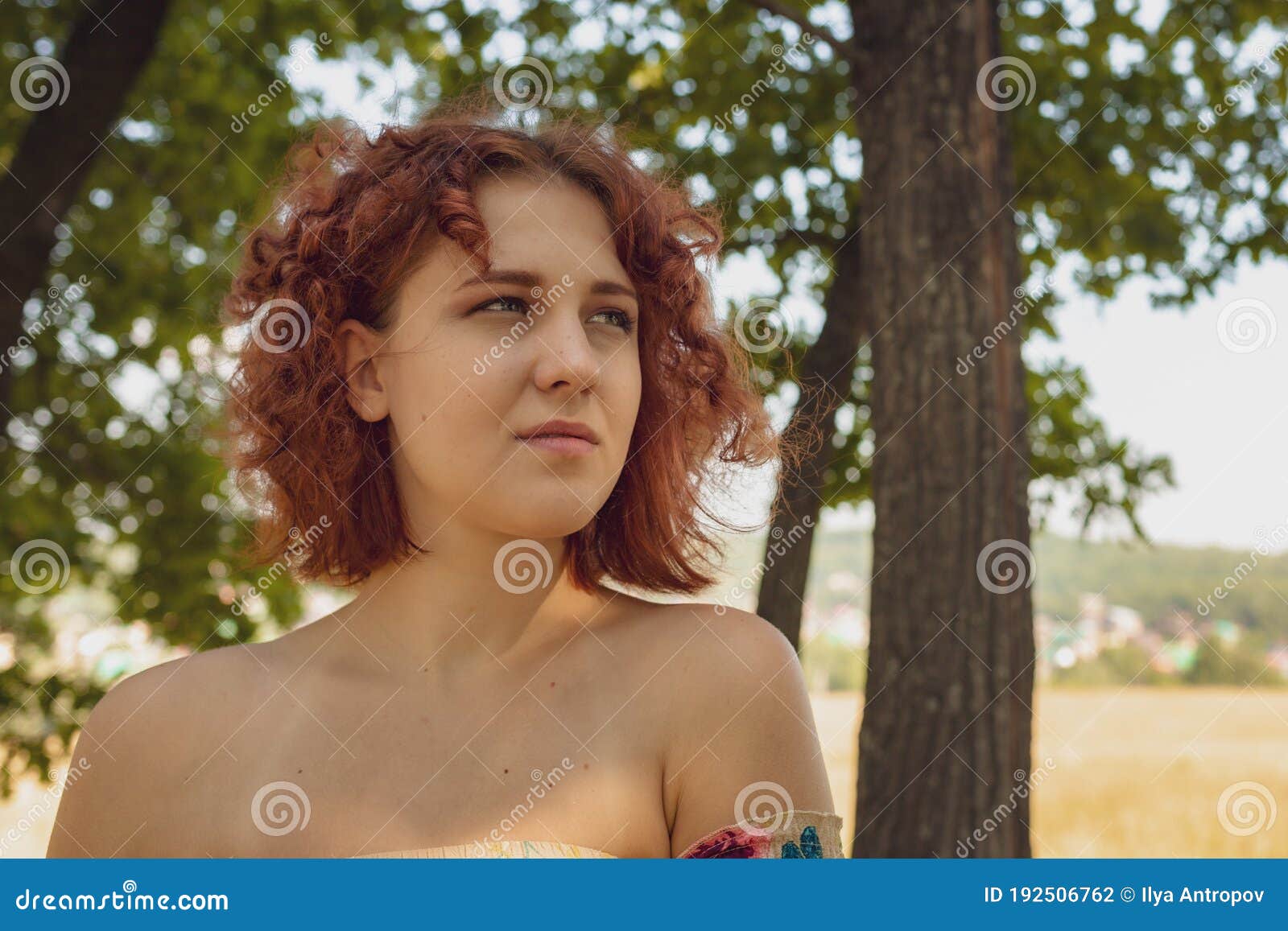 Red Haired Curly Haired Girl In A Summer Dress Posing In The Village