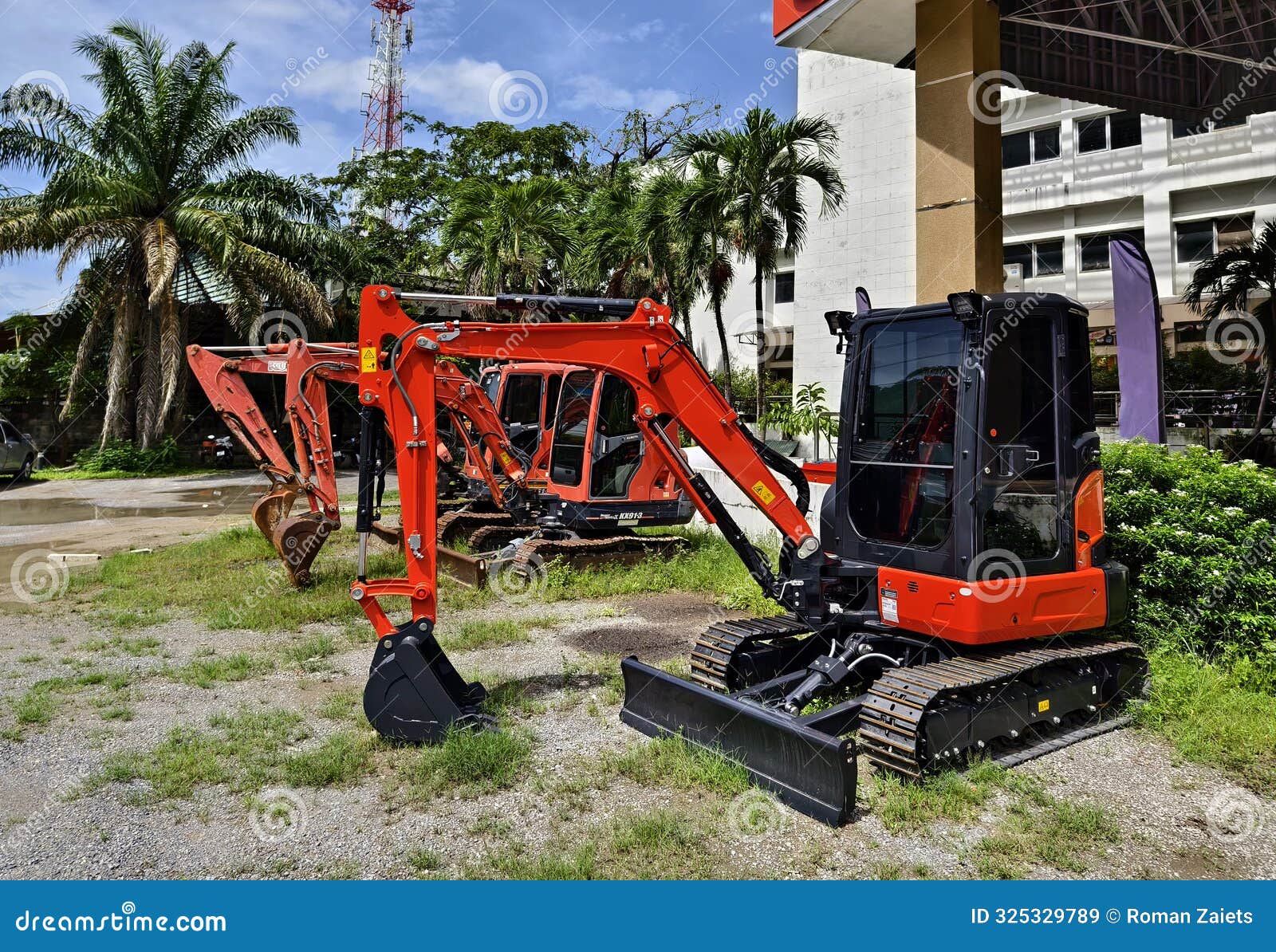 Red Large Excavators are Stationed in a Green Field in Front of a ...