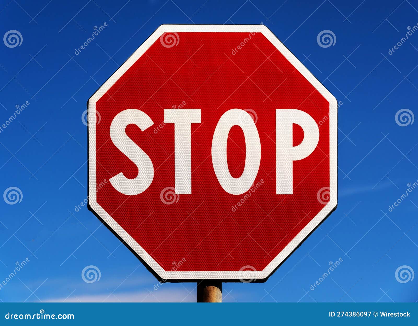 Red Octagonal Stop Sign Mounted on a Metal Post with a Blue Sky ...