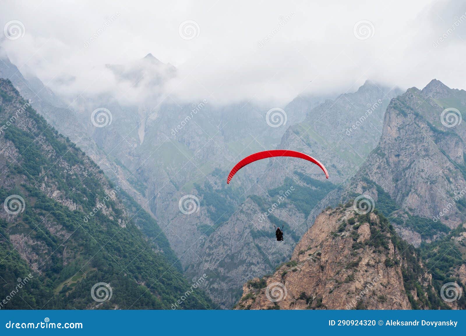 Red Paraglider Flies Against the Background of Mountains and Clouds ...