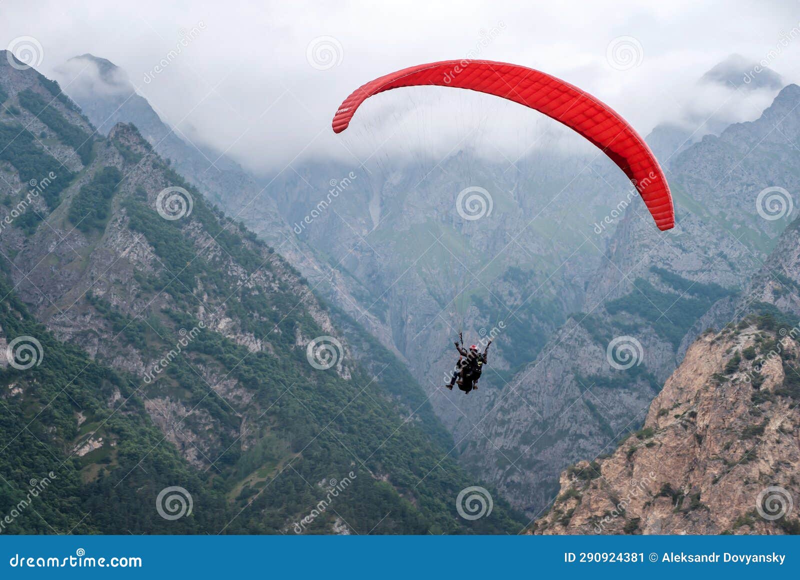 Red Paraglider Flies Against the Background of Mountains and Clouds ...
