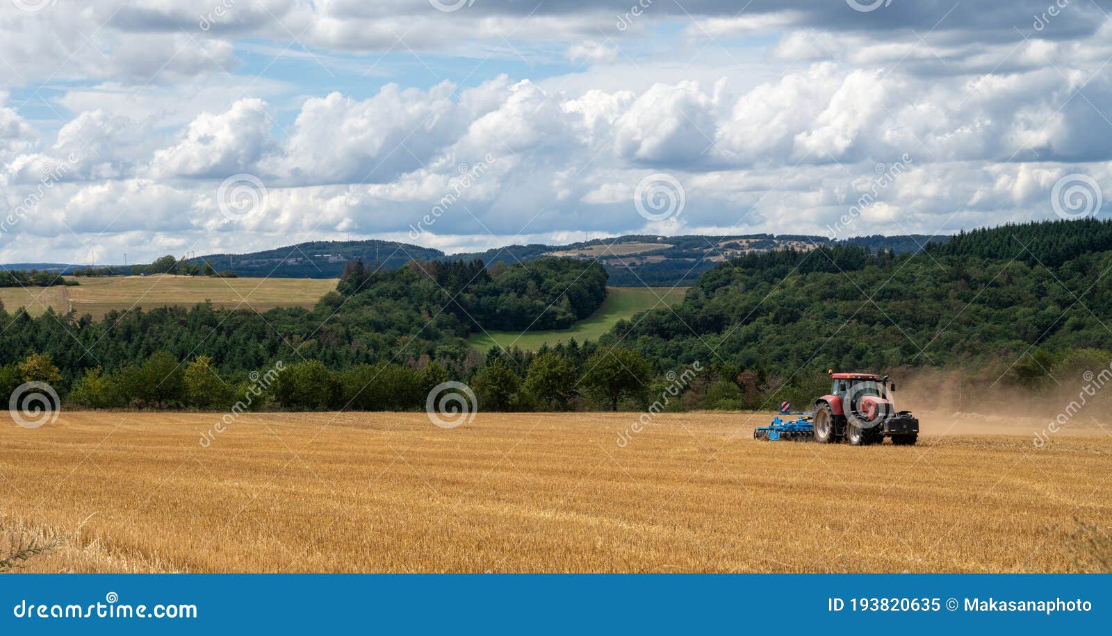 Red Tractor Pulling a Blue Field Cultivator Across a Harvested Wheat ...
