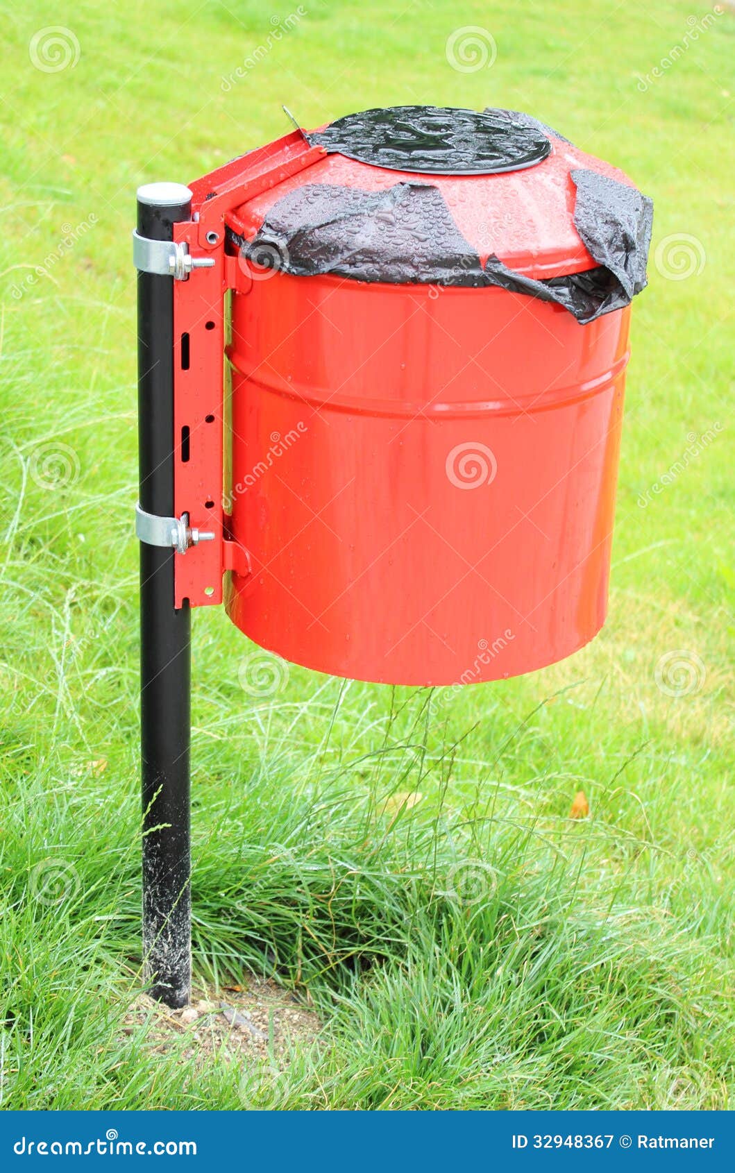 Red and Wet Garbage Basket in a Park on a Background of Green Grass ...