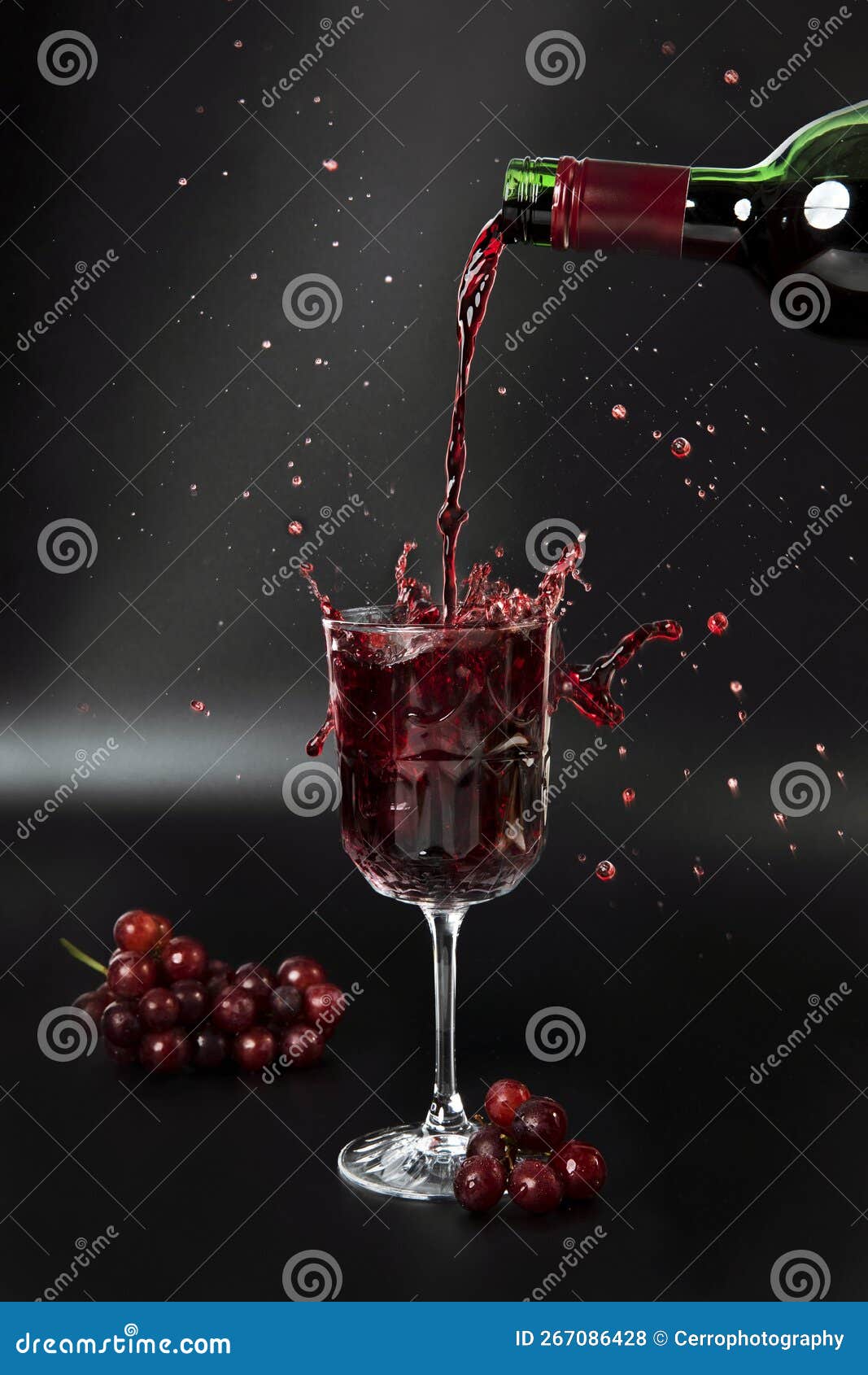 Red Wine is Poured into a Wine Glass on a Black Background with Grapes ...