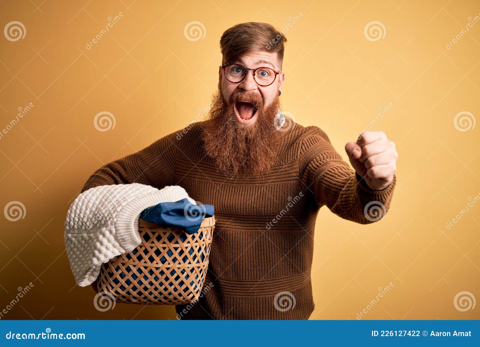 Redhead Irish Man With Beard Doing Housework Laundry Over Yellow Background Screaming Proud And