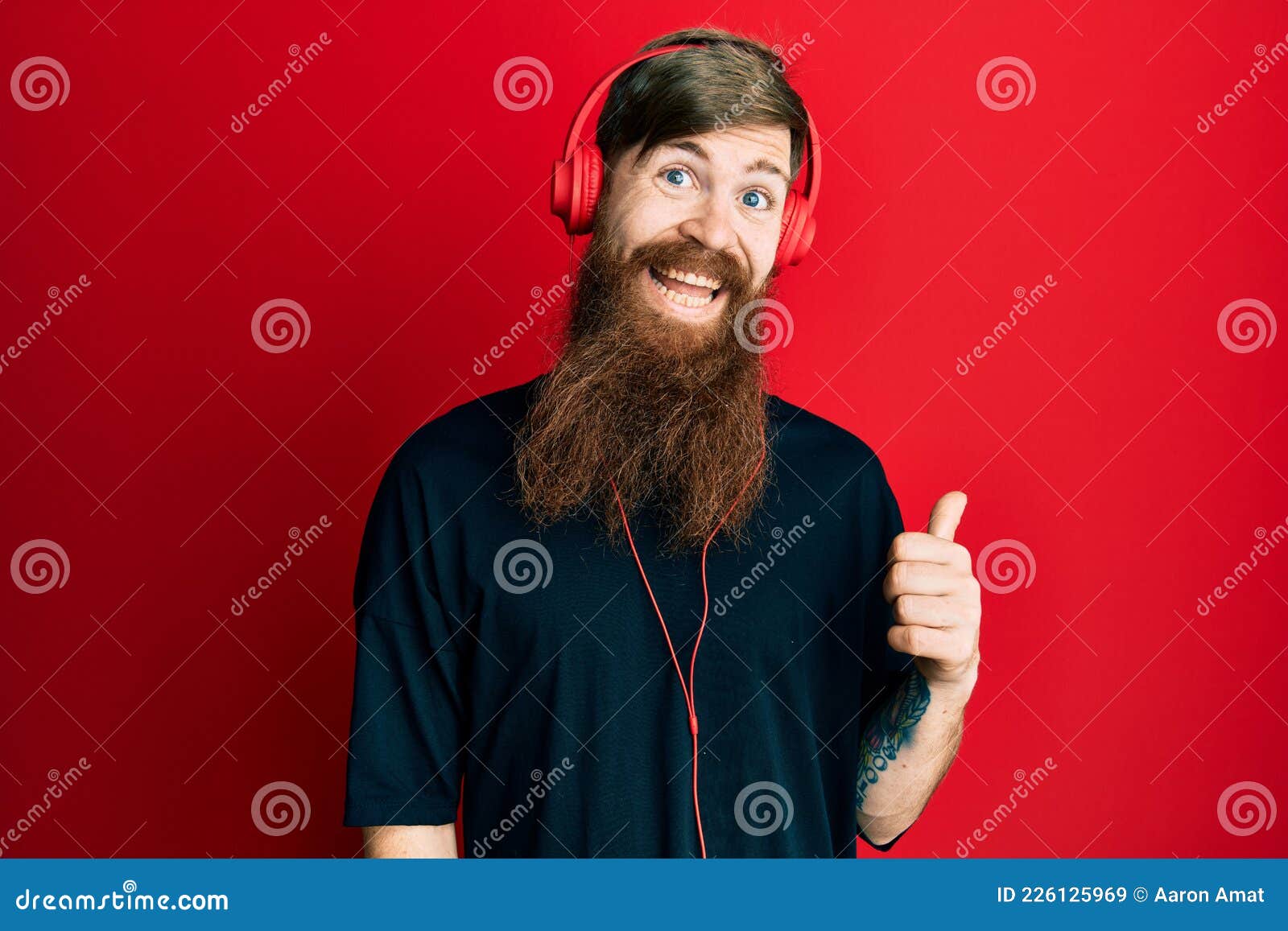 Redhead Man With Long Beard Listening To Music Using Headphones Smiling
